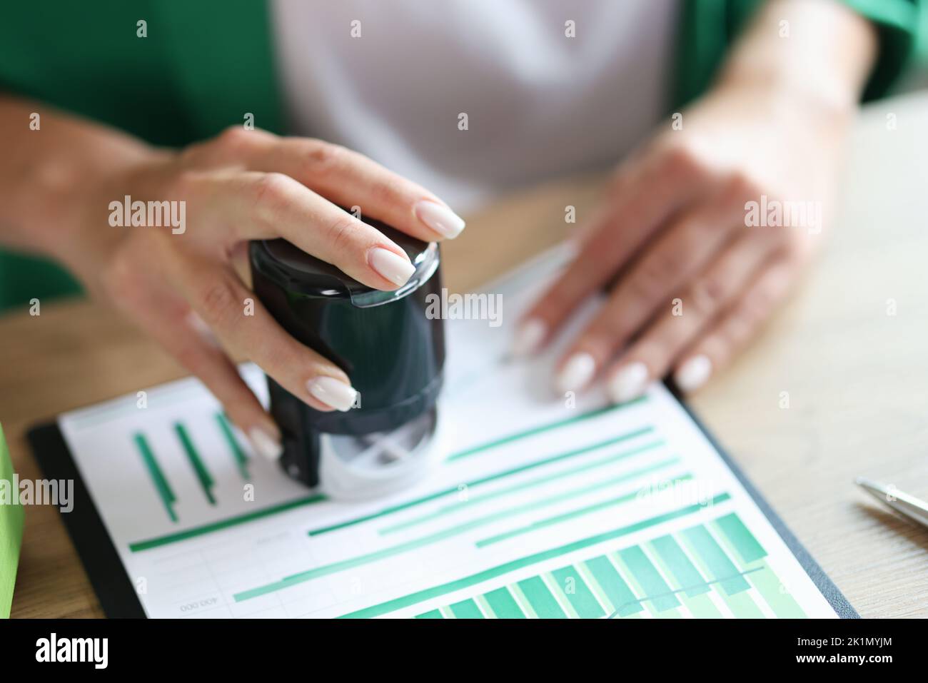 Businesswoman at table puts seal on financial documents with charts ...