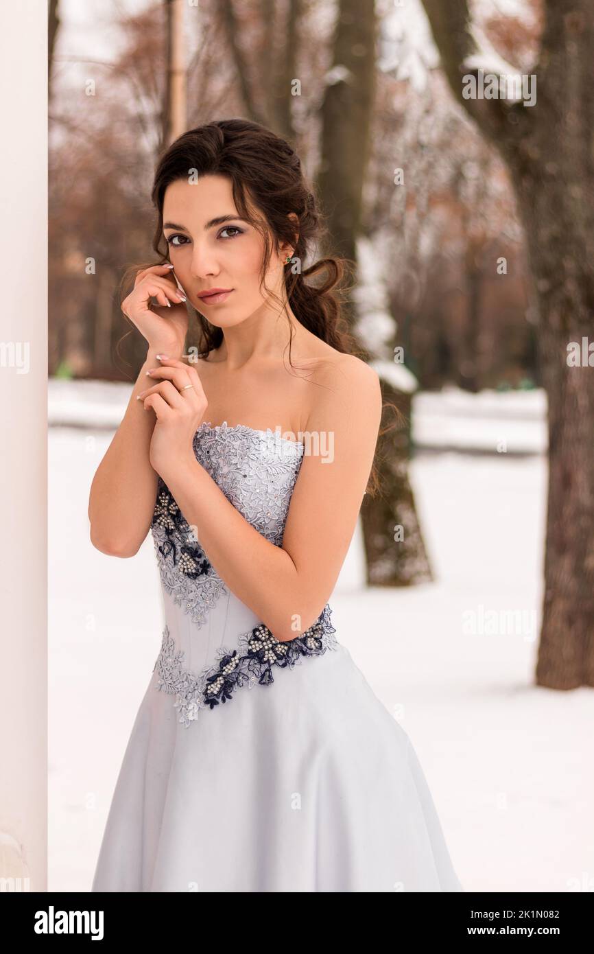 Beautiful woman in a luxurious blue fairy-tale dress in a snowy forest ...