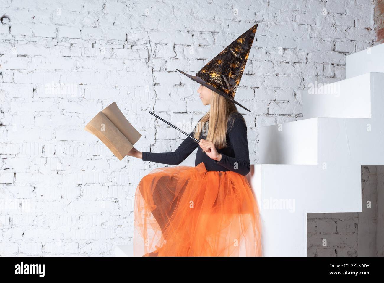 Kids Halloween. A beautiful sweet girl in a witch costume, wearing a ...