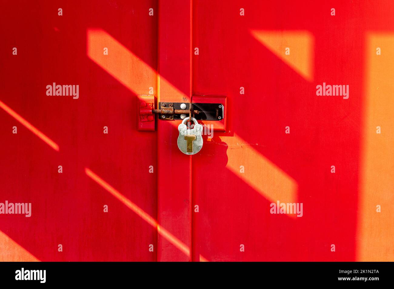 Red door bolted with a padlock Stock Photo - Alamy