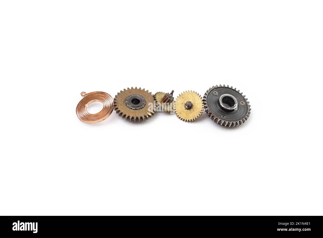 tiny gears and a spring arranged in a line, isolated on white ...