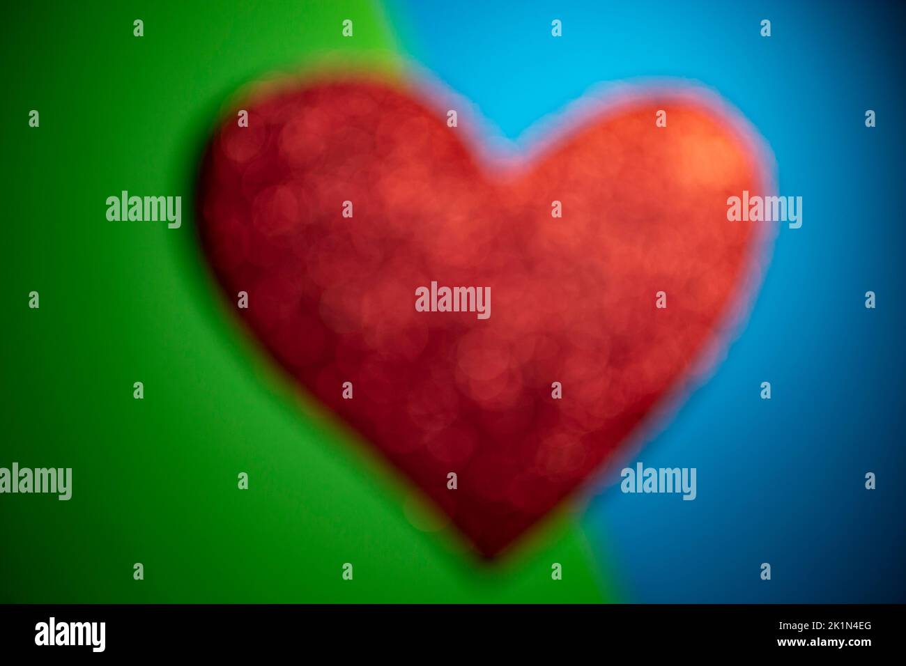 red defocused heart on green and blue background. color blur backdrop ...