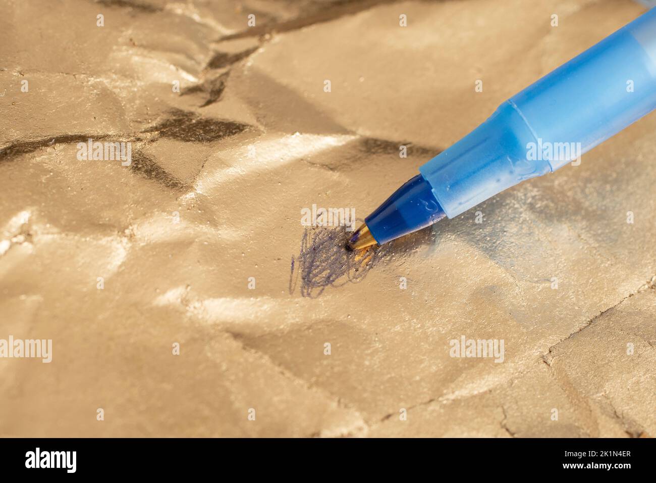 blue ball pen tip scribbling on golden paper texture. abstract backdrop ...