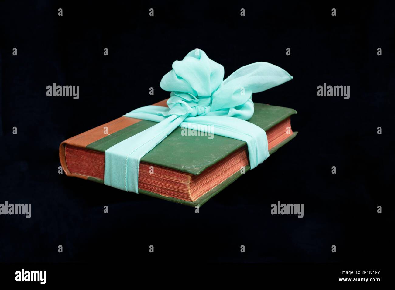 Levitating green book with red pages, tied with a turquoise bow ...