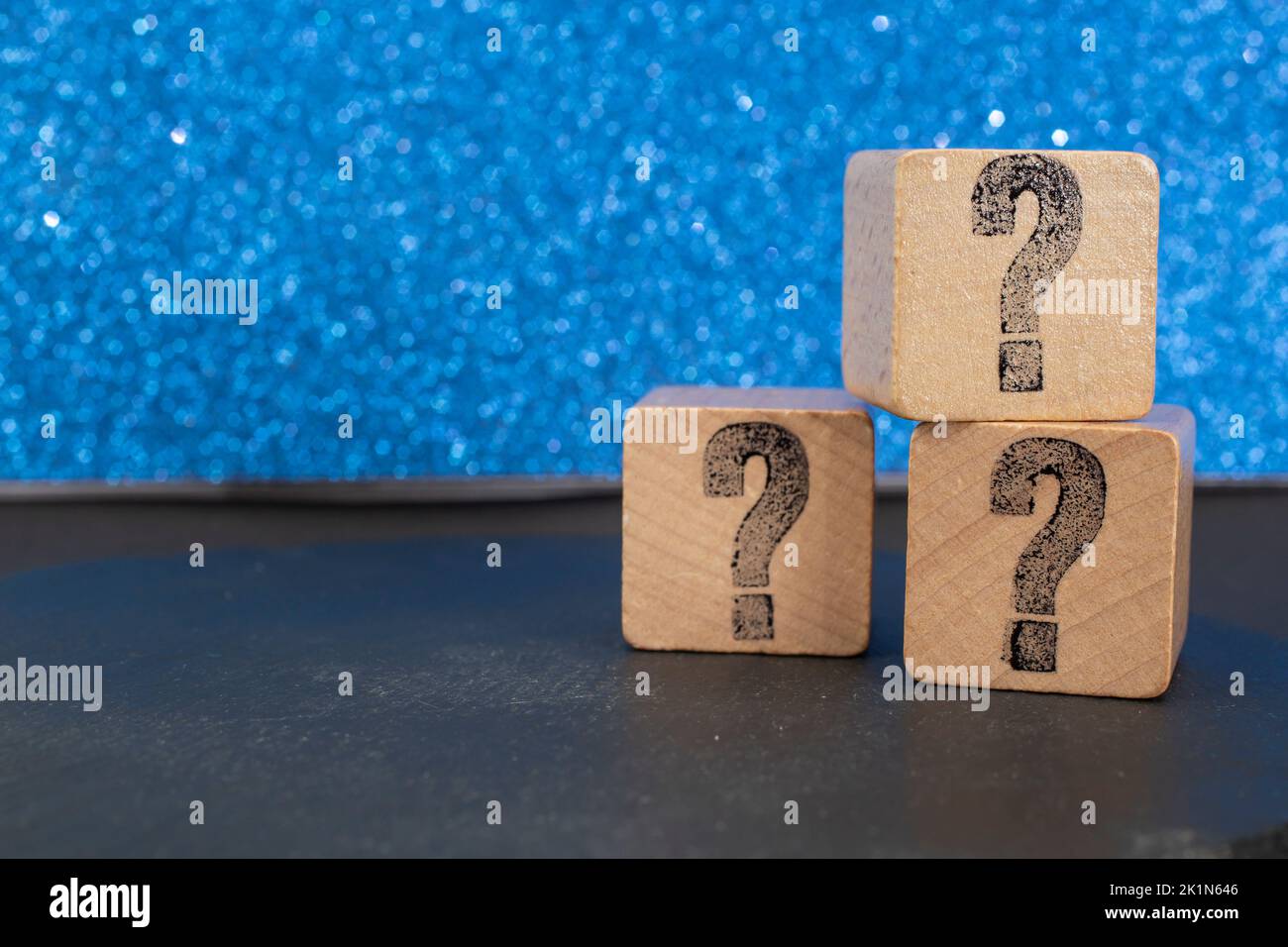 question marks on wooden cubes stacked on blue glitter background Stock ...
