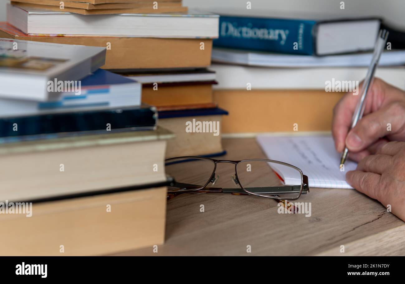 A person, student taking study notes from a pile of printed books Stock ...