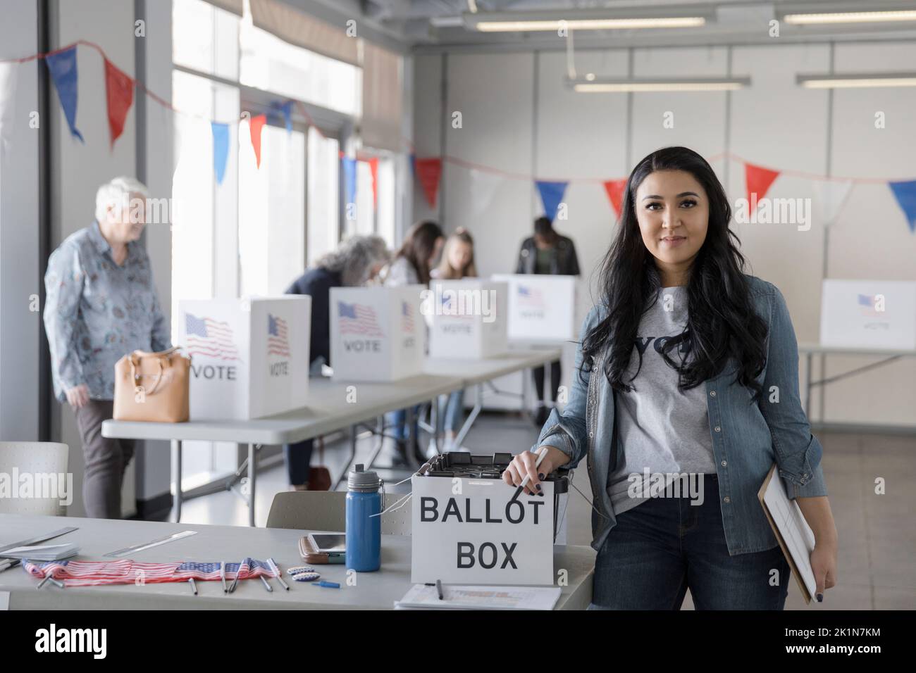Portrait confident female volunteer at ballot box in polling place ...