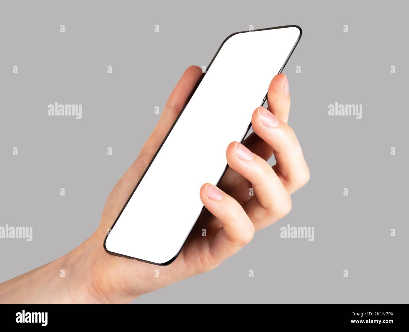 Hand holding phone mockup on grey background. Angled view. template ...