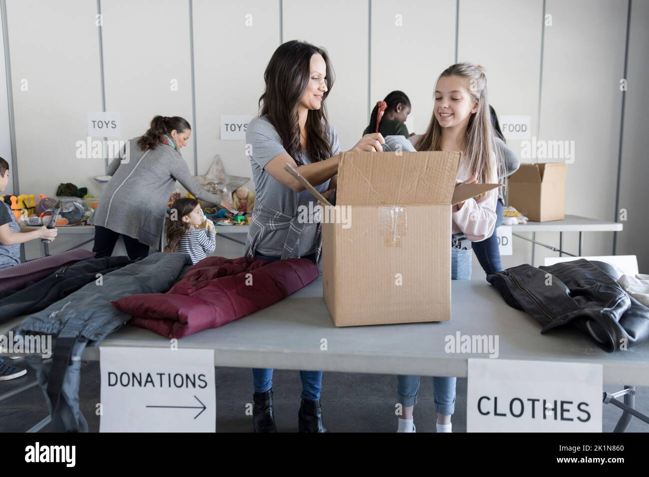 Mother and daughter sorting donations in community center Stock Photo ...