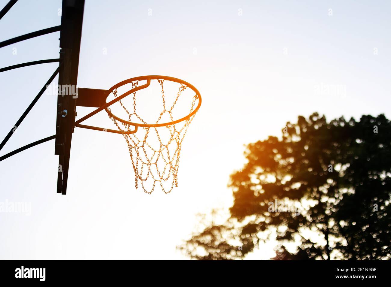 silhouette of basketball hoop with metal net on wooden backboard on ...