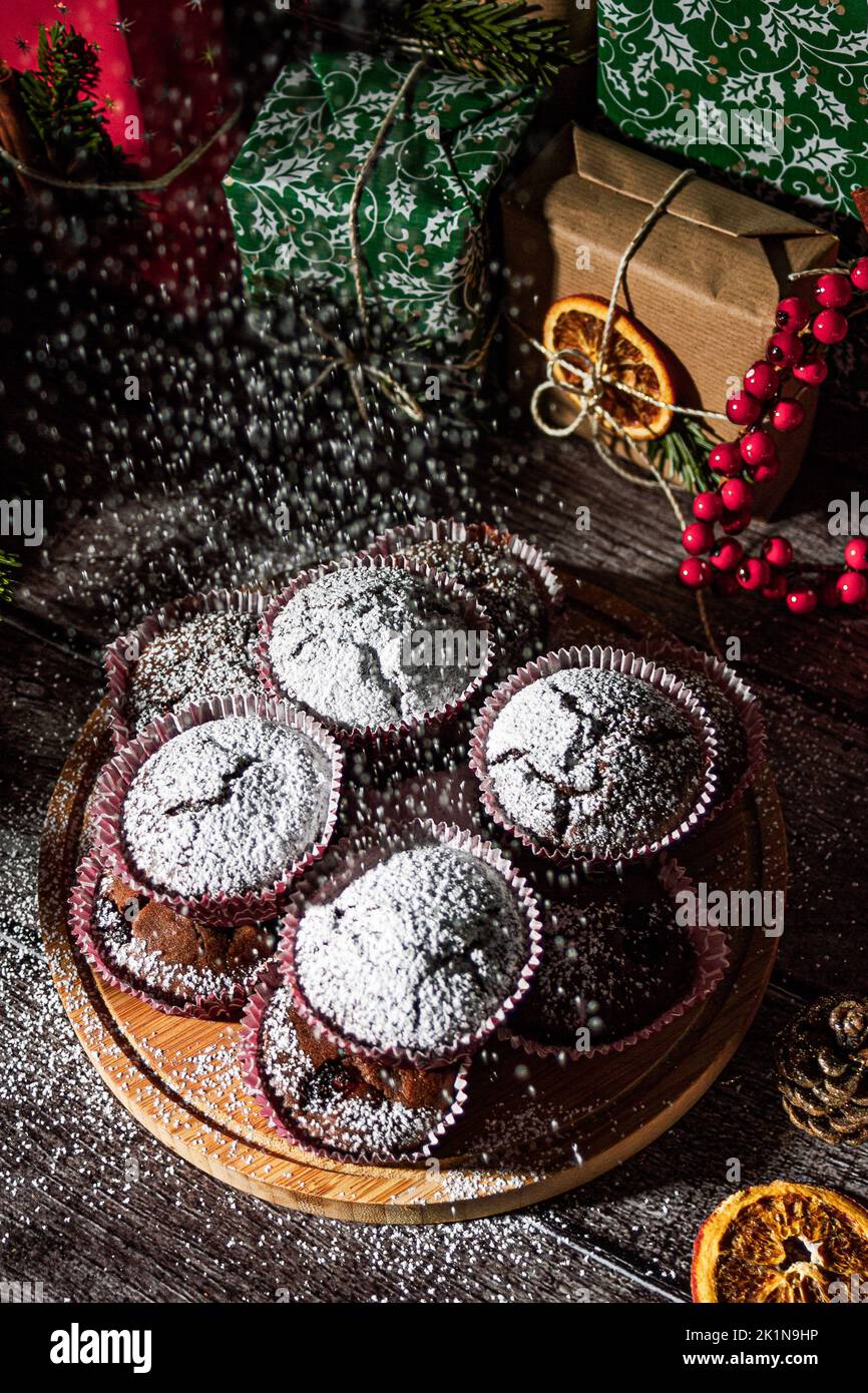 Powdered sugar muffins on wooden plate and Christmas gifts. New year ...
