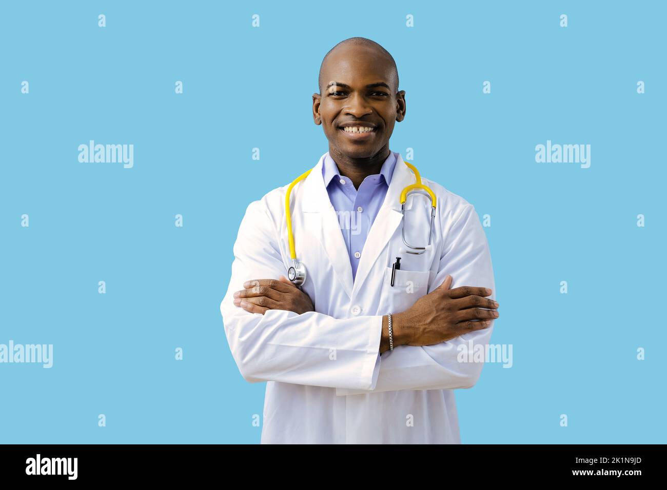 Doctor smiling with folded arms wearing lab coat indoors studio Stock ...
