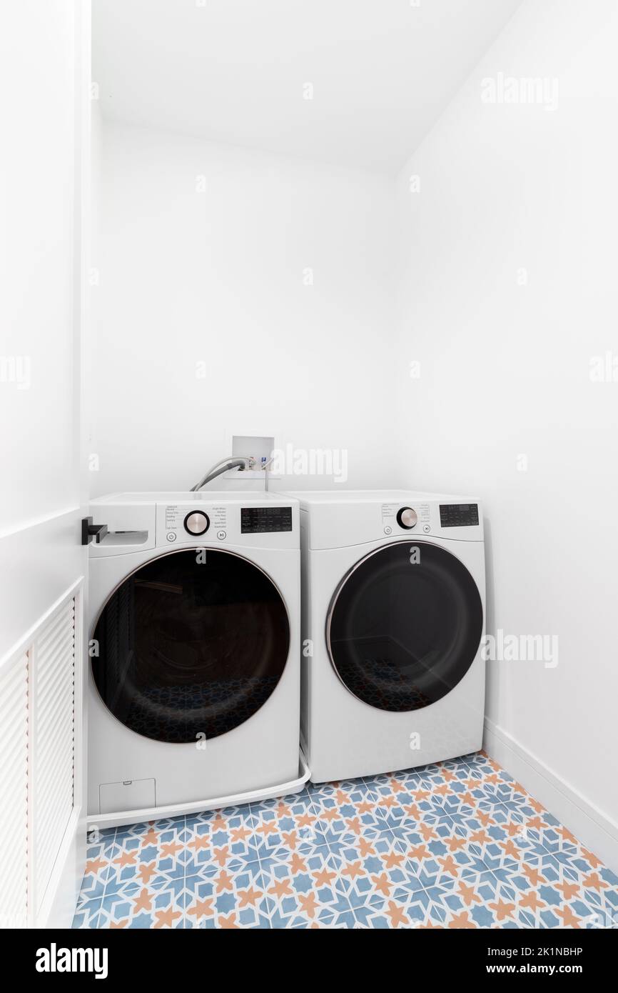A laundry room with a white washer and dryer on a mosaic tile flooring ...