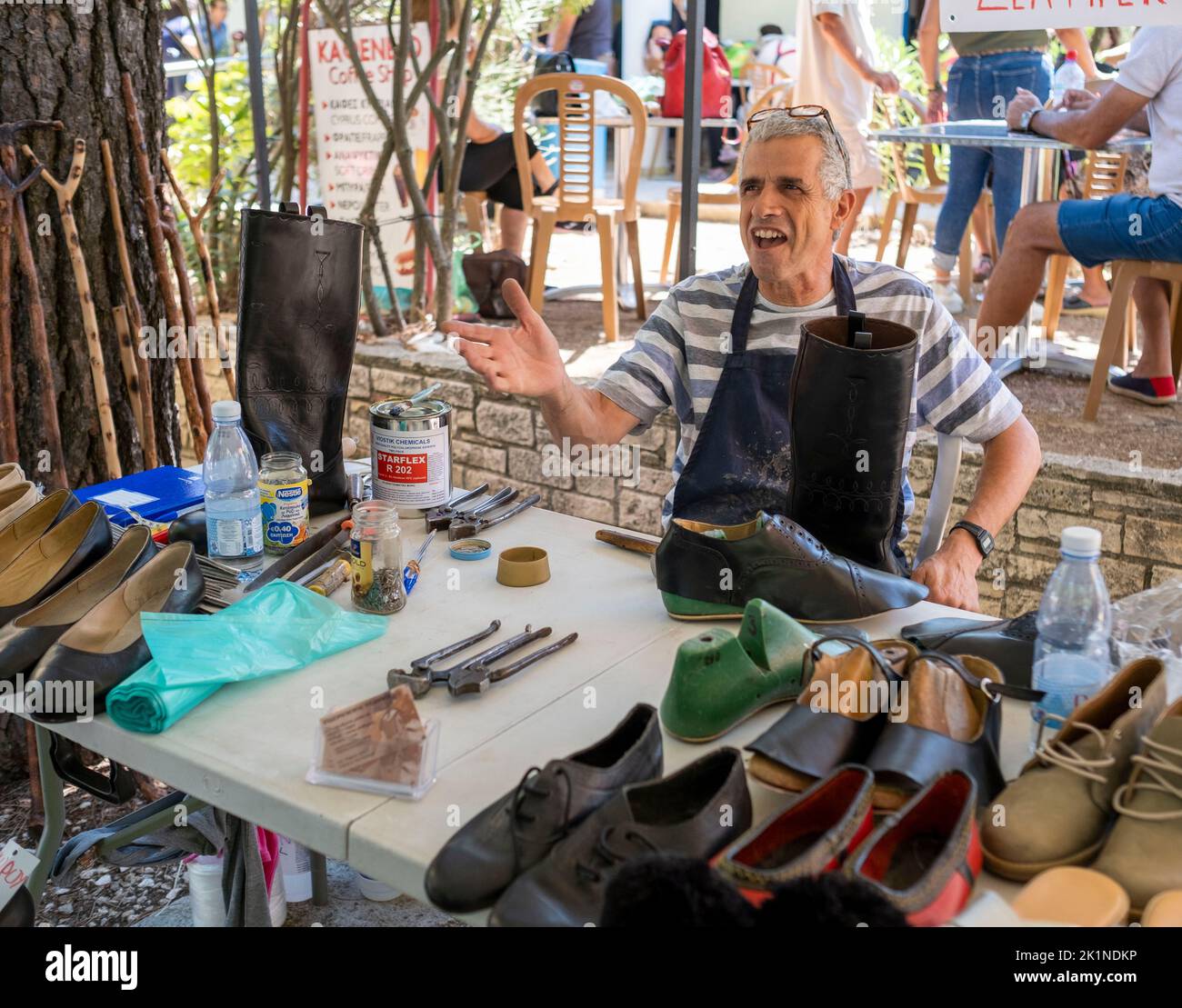 A cobbler speaks with customers at his stall during the Statos-Ayios ...