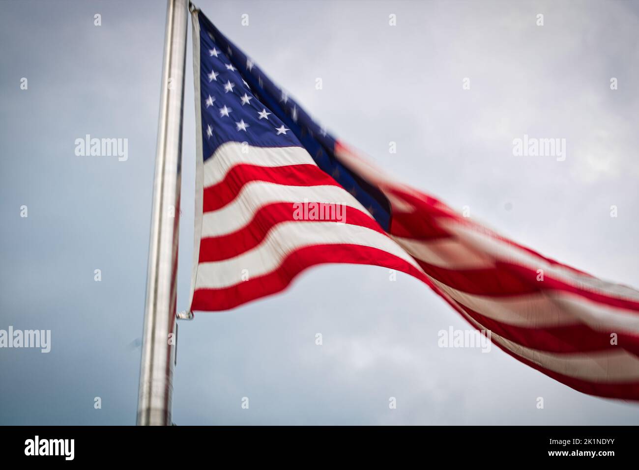 The American Flag waves in the breeze in front of an overcast late ...