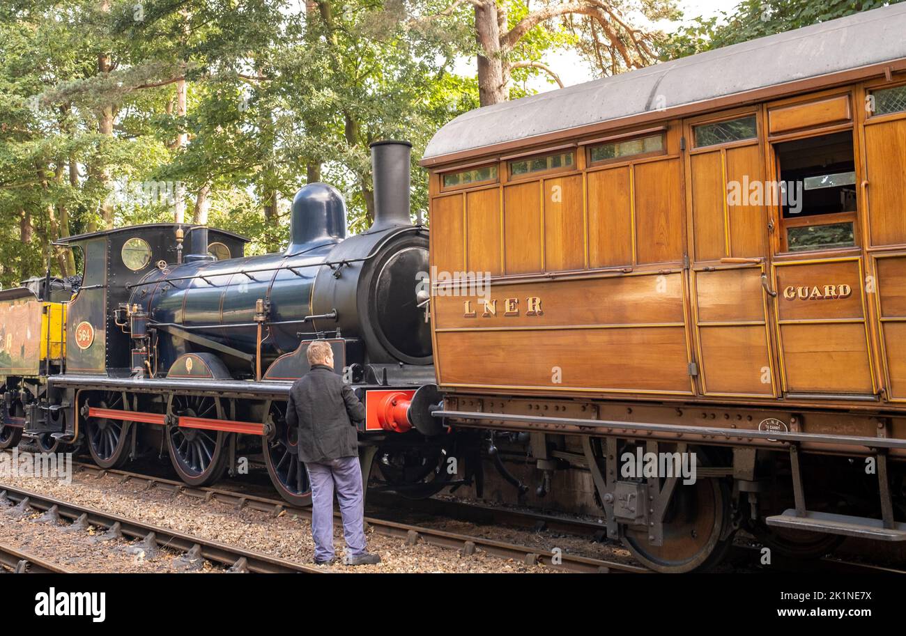 42. Engineer looking at a vintage steam train and wooden passenger ...