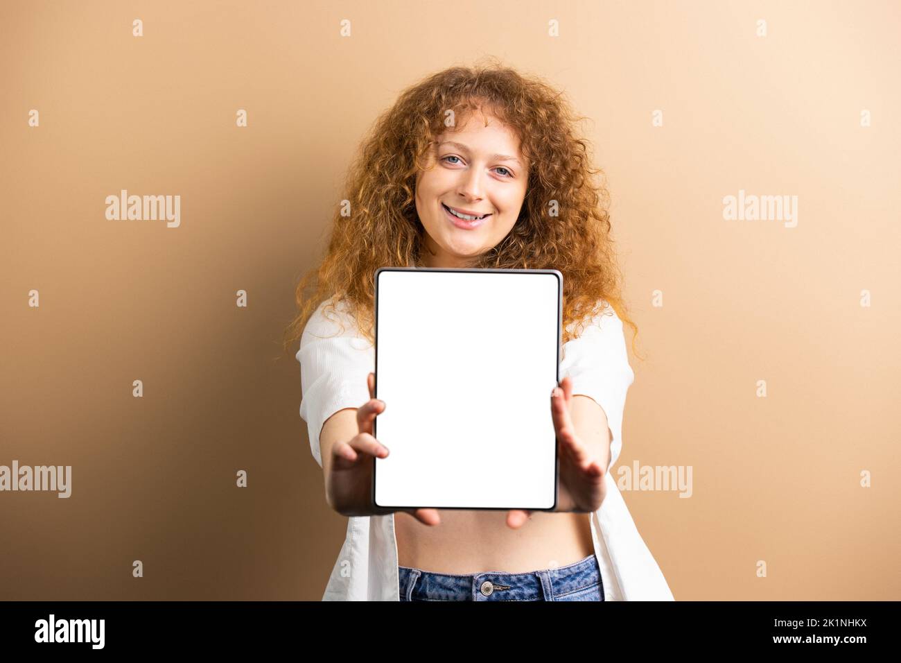 Beautiful woman model with curly hairstyle holding tablet in her hands ...