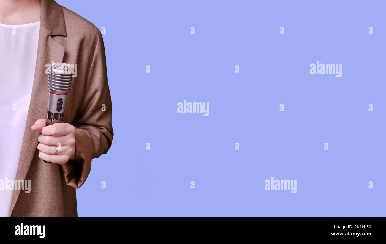 Woman teacher holding microphone in hand on studio blue background ...