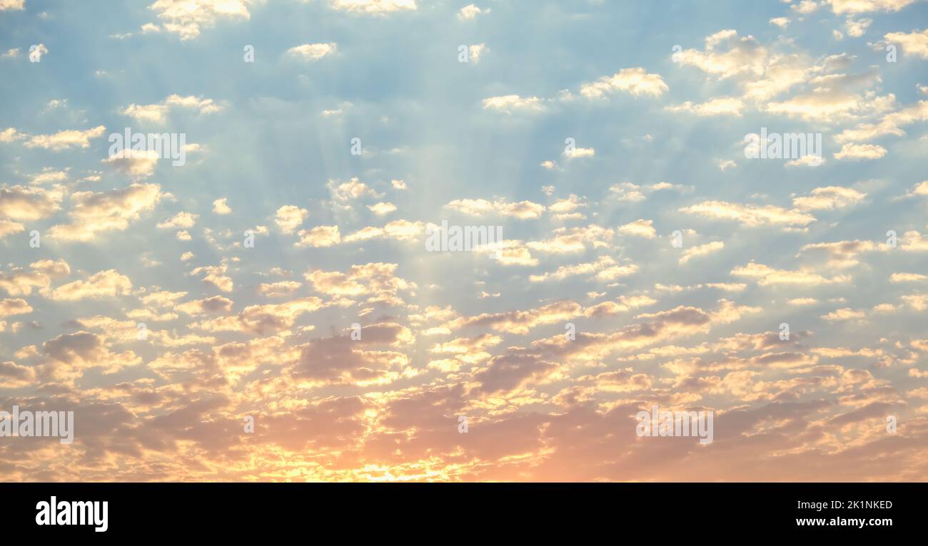 Blue sky with twilight clouds. The sun is setting over the horizon. Yellow dawn. Red sunset ...
