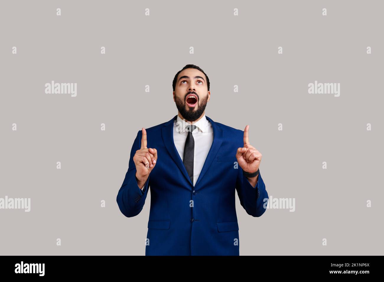 Bearded man looking astonished and pointing up copy space, showing ...