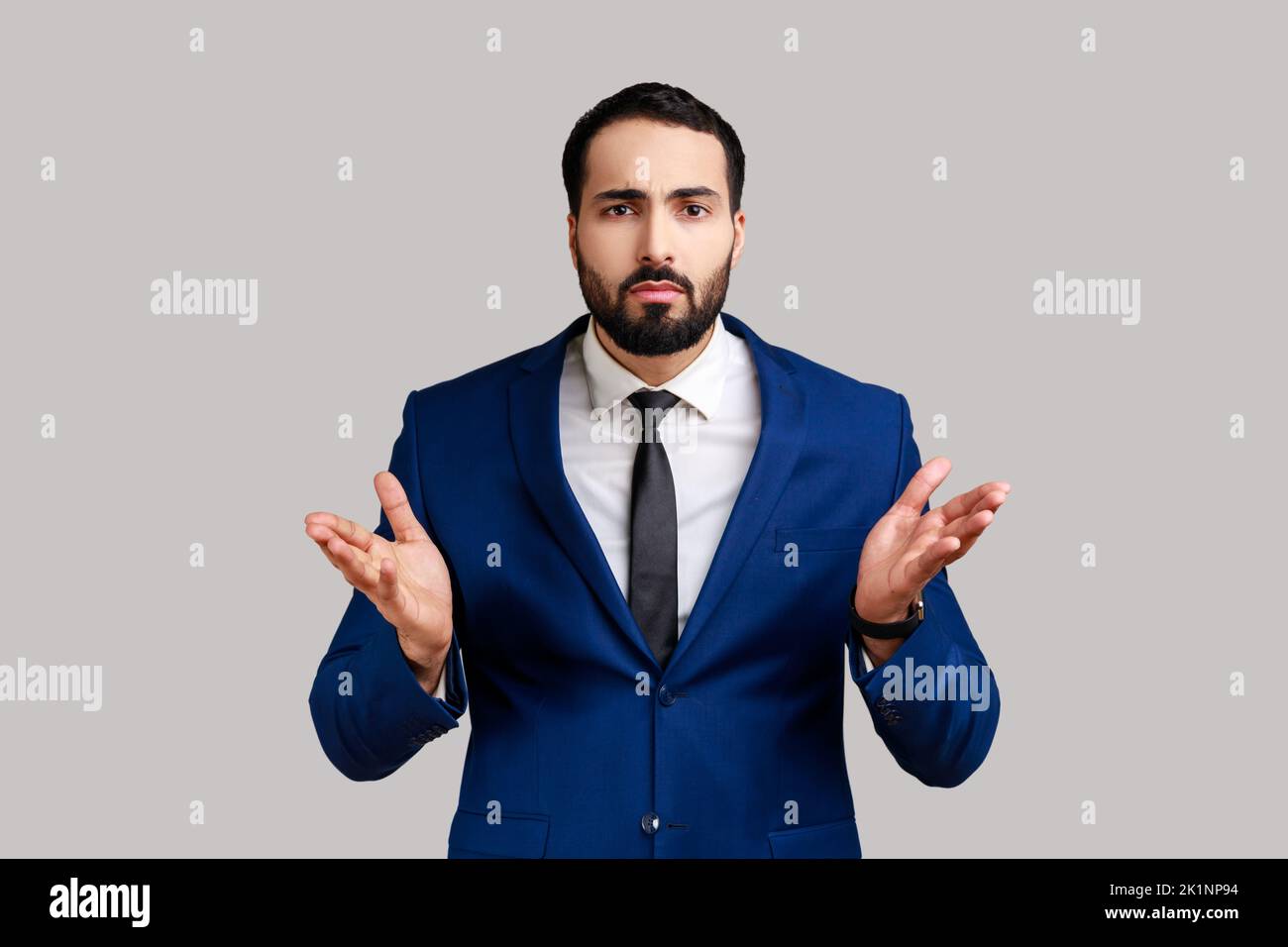 Portrait of bearded man standing with raised hands and confused ...