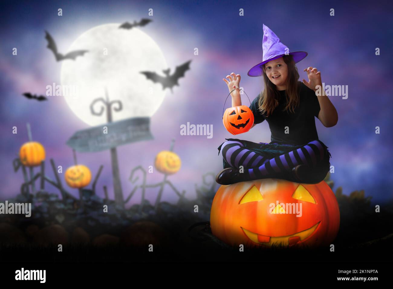 Little witch sitting on giant pumpkin lantern on Halloween night. Huge ...
