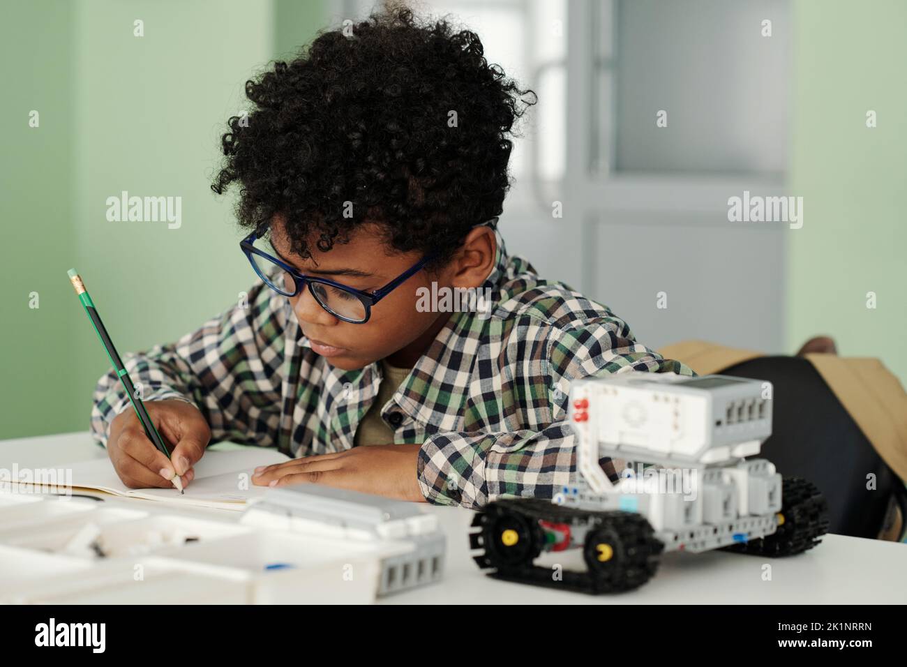 Clever and diligent learner with pencil making notes or drawing sketch ...