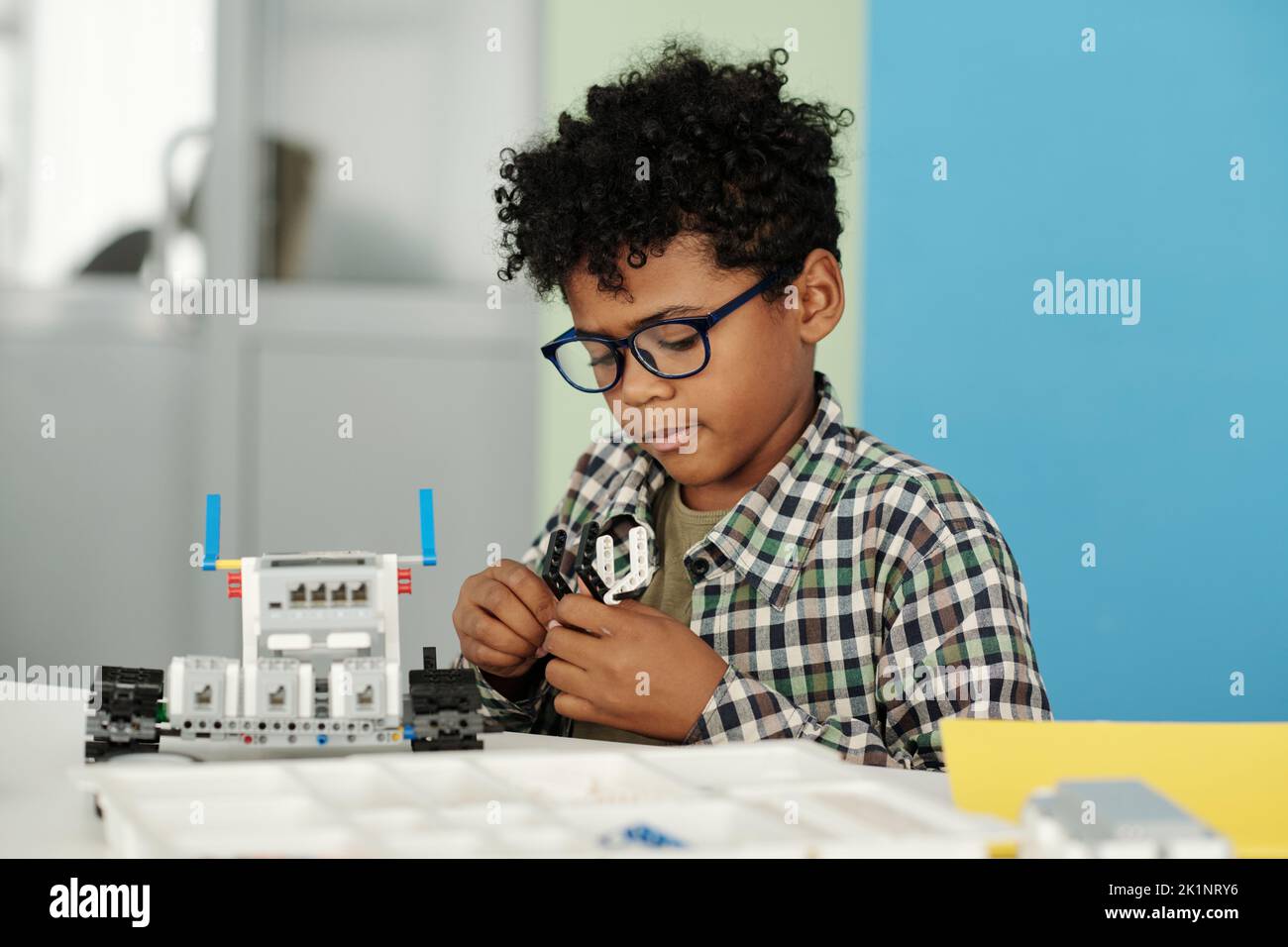 Clever little boy in casualwear and eyeglasses connecting details of ...