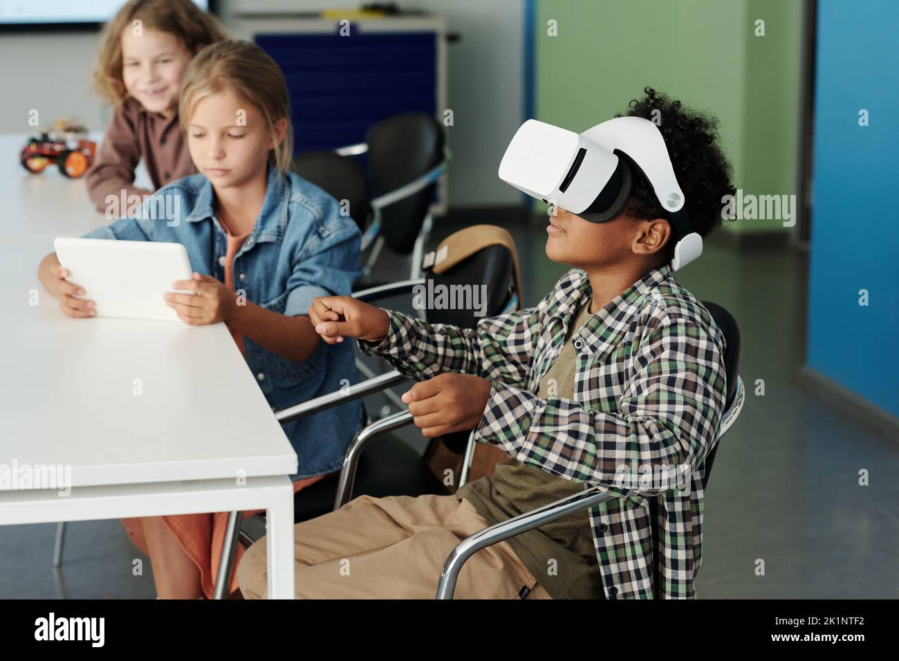 Side view of cute African American schoolboy in vr headset controling ...
