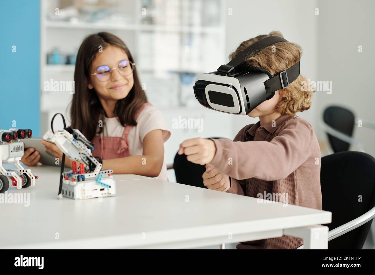Cute schoolboy in vr headset playing virtual game while sitting by his ...