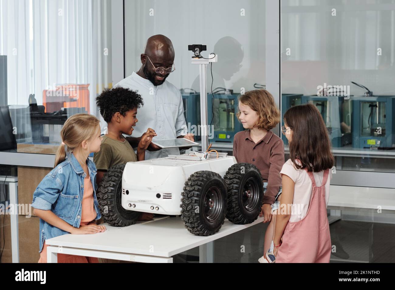 Group of clever intercultural pupils and their teacher of robotics ...