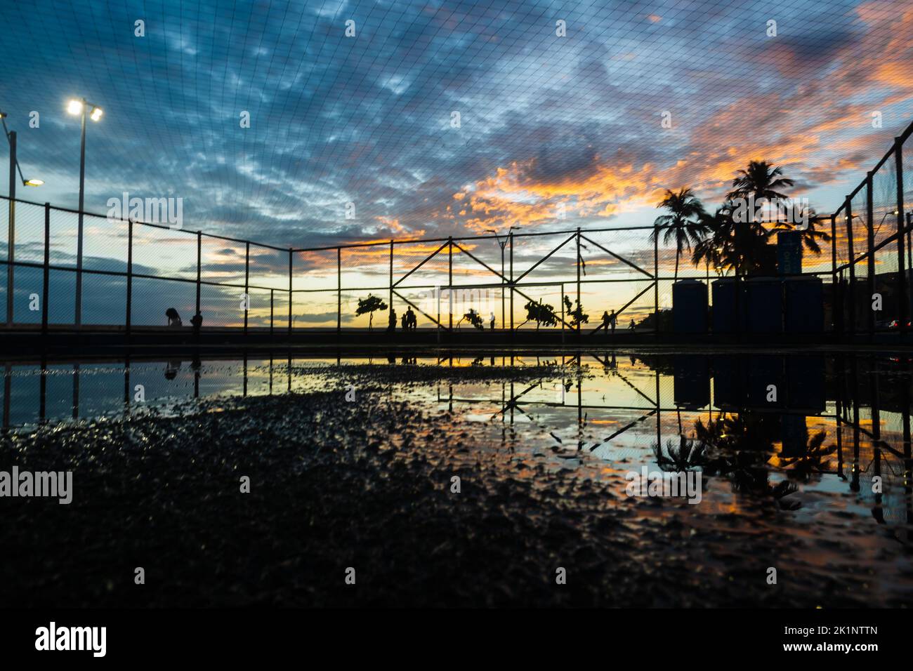 Silhouette of a sport court wet from the rain against dramatic sunset ...