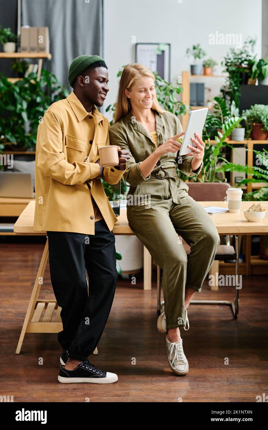 Young smiling blond businesswoman pointing at graphic financial data on ...