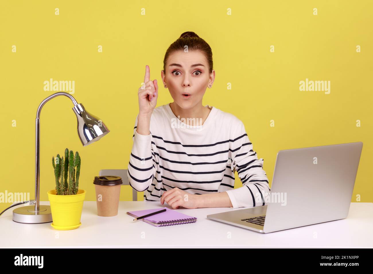 Excited woman manager in striped shirt looking surprised by genius idea ...
