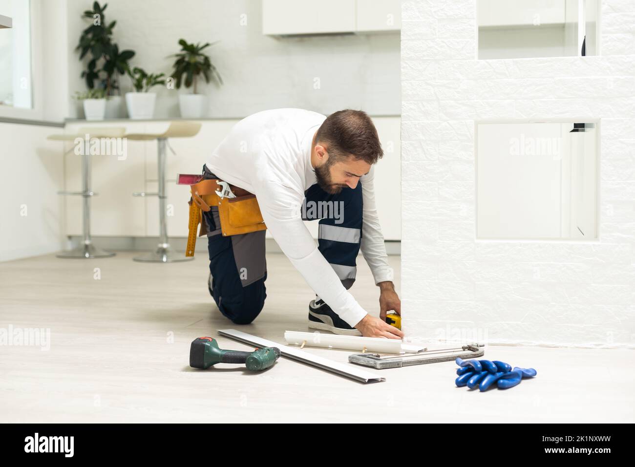 The craftsman measures the length of the plinth for cutting, installing ...