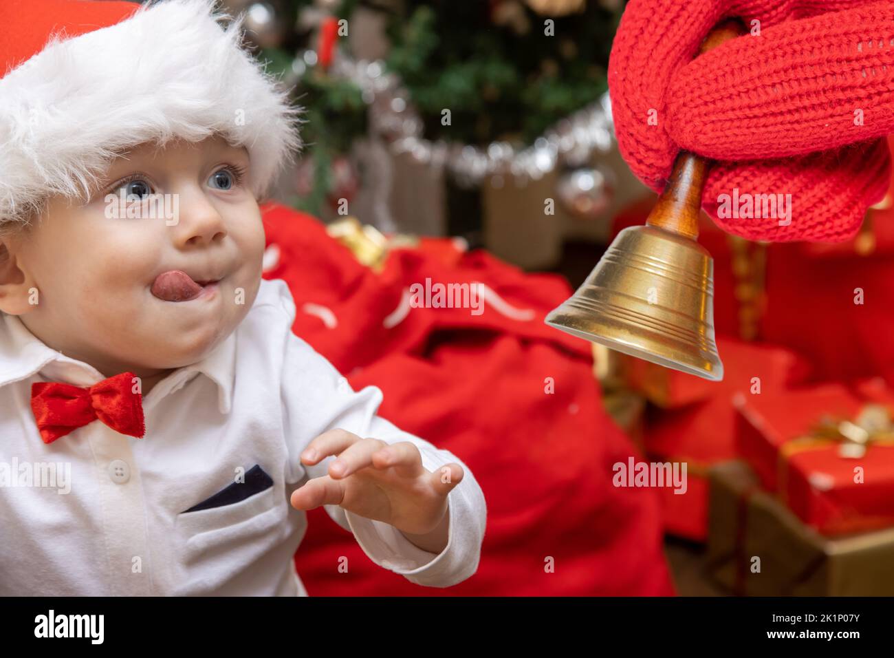 Little boy with a Santa Claus hat looks at bell in a hand Stock Photo ...