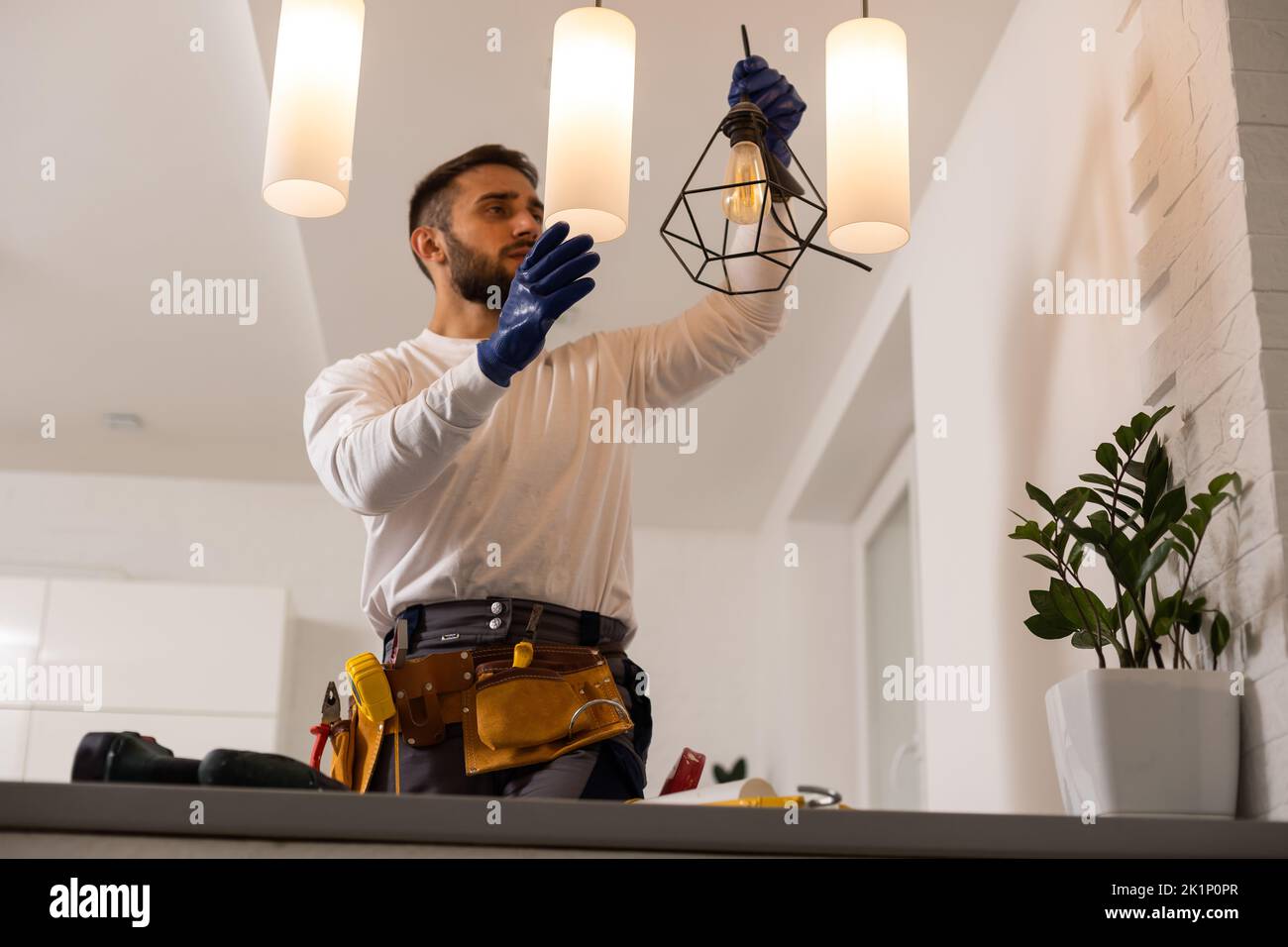 Electrician worker man assembling electric lamps in new apartment Stock ...