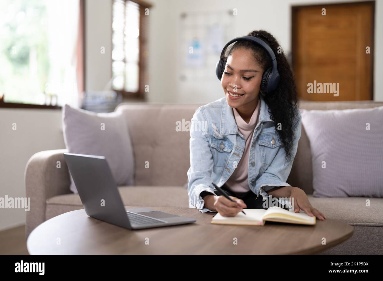 Portrait woman wearing headphones watching webinar write notes study ...
