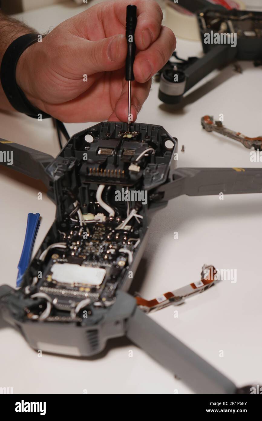 close up of mans hands repairing a drone on white table with different ...