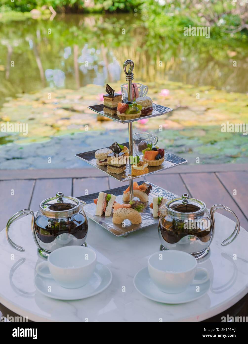 Afternoon tea at a water pond, high tea in a tropical garden in ...