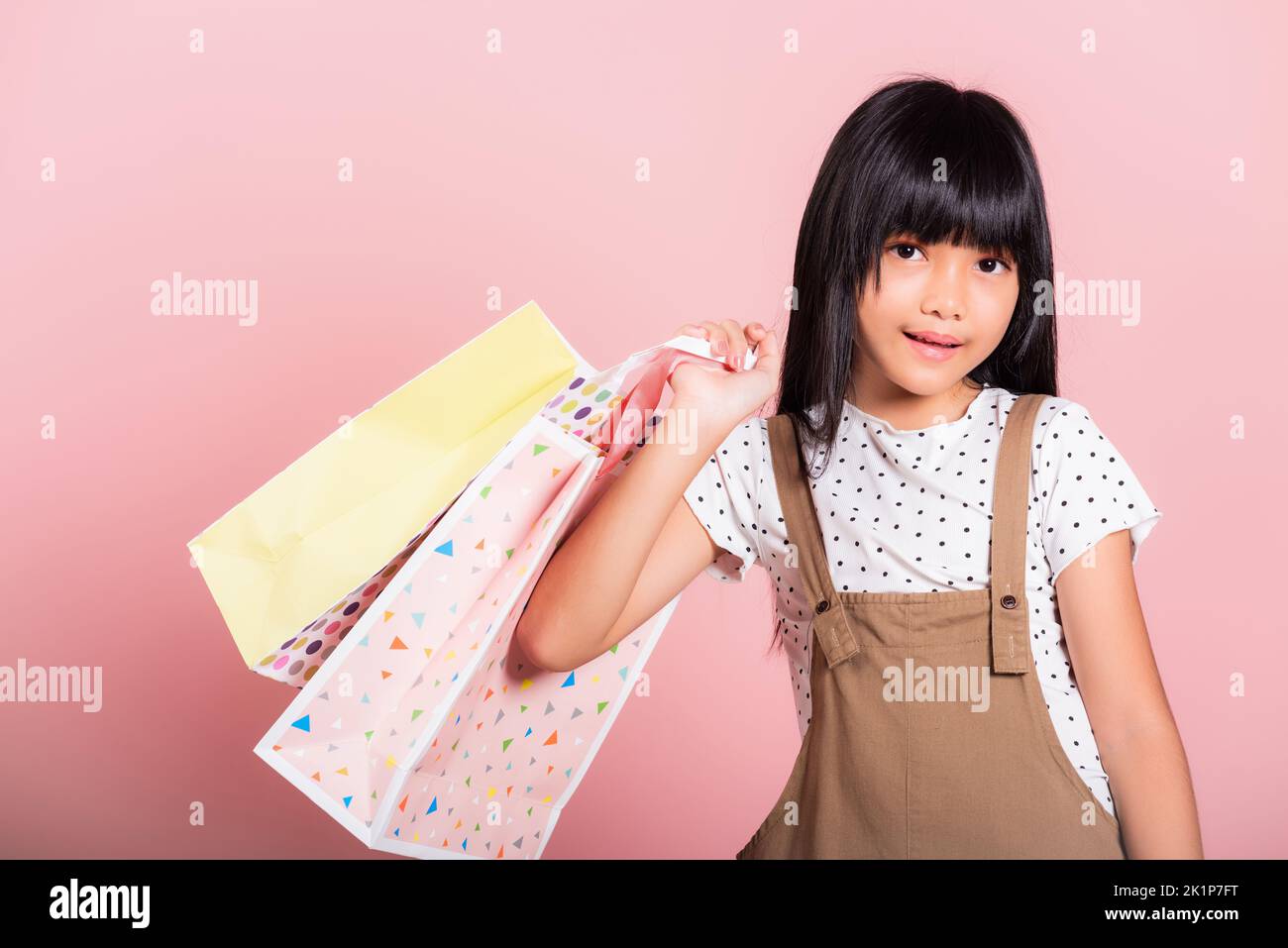 Asian little kid 10 years old smiling holding multicolor shopping bags ...