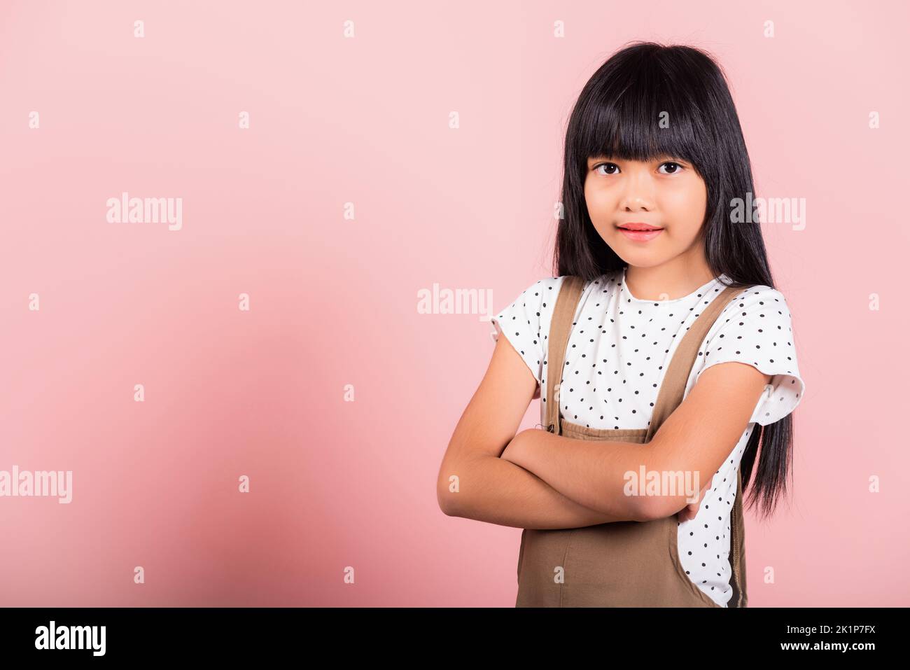 Asian little kid 10 years old smiling with arms crossed at studio shot ...