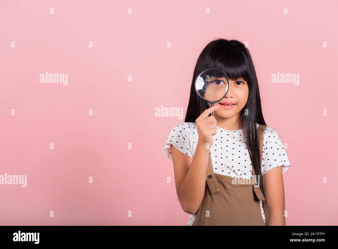 Asian little kid 10 years old funny looking through magnifying glass at ...