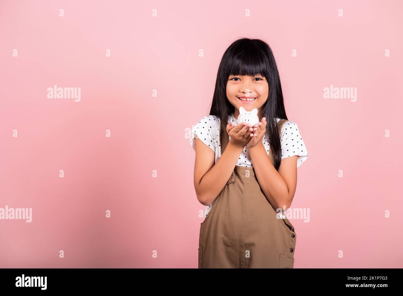 Asian little kid 10 years old holding piggy bank and looking at camera ...