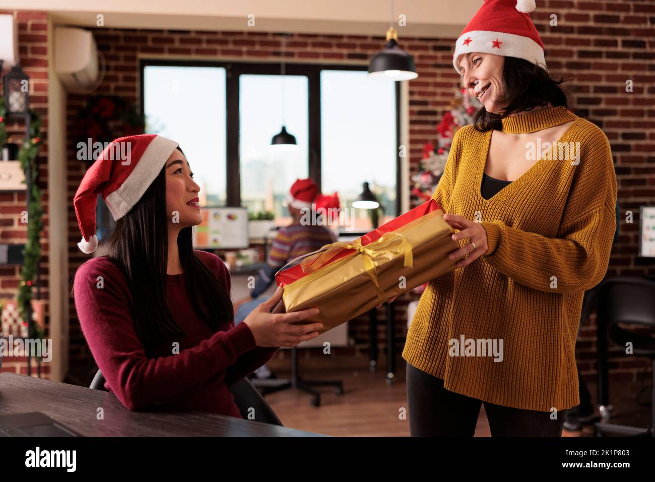 Diverse women exchanging present box on christmas eve celebration at ...