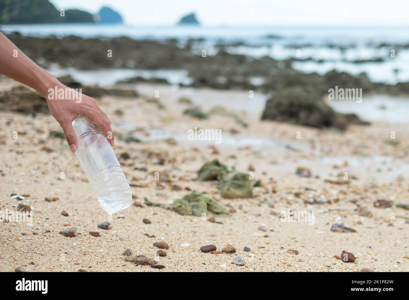 Volunteer hand pick up trash, plastic Bottle garbage on the beach ...
