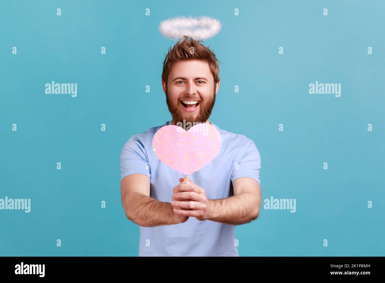 Portrait of bearded angelic man with holy nimbus holding in hands pink ...