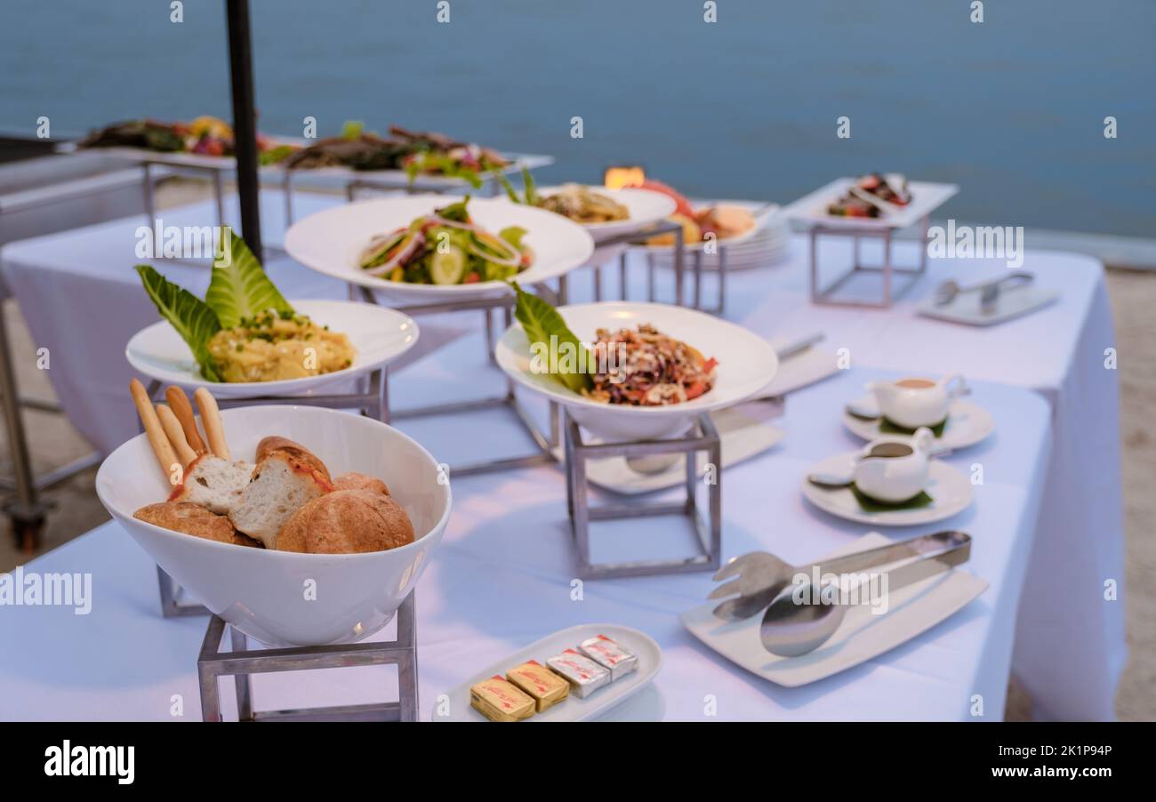 Buffet table by the ocean with fresh salad and bread and Thai food ...