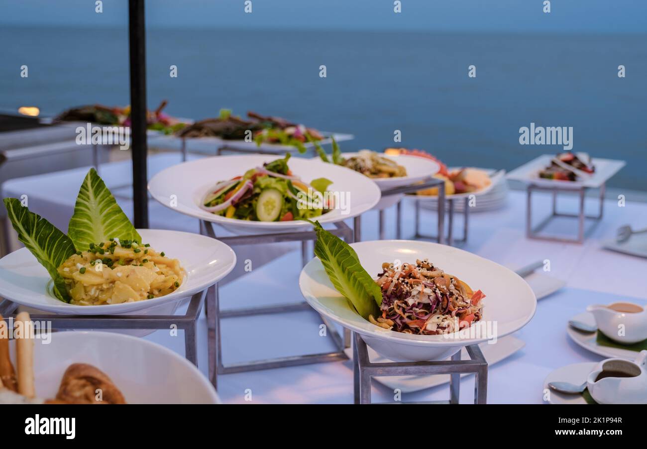 Buffet table by the ocean with fresh salad and bread and Thai food ...