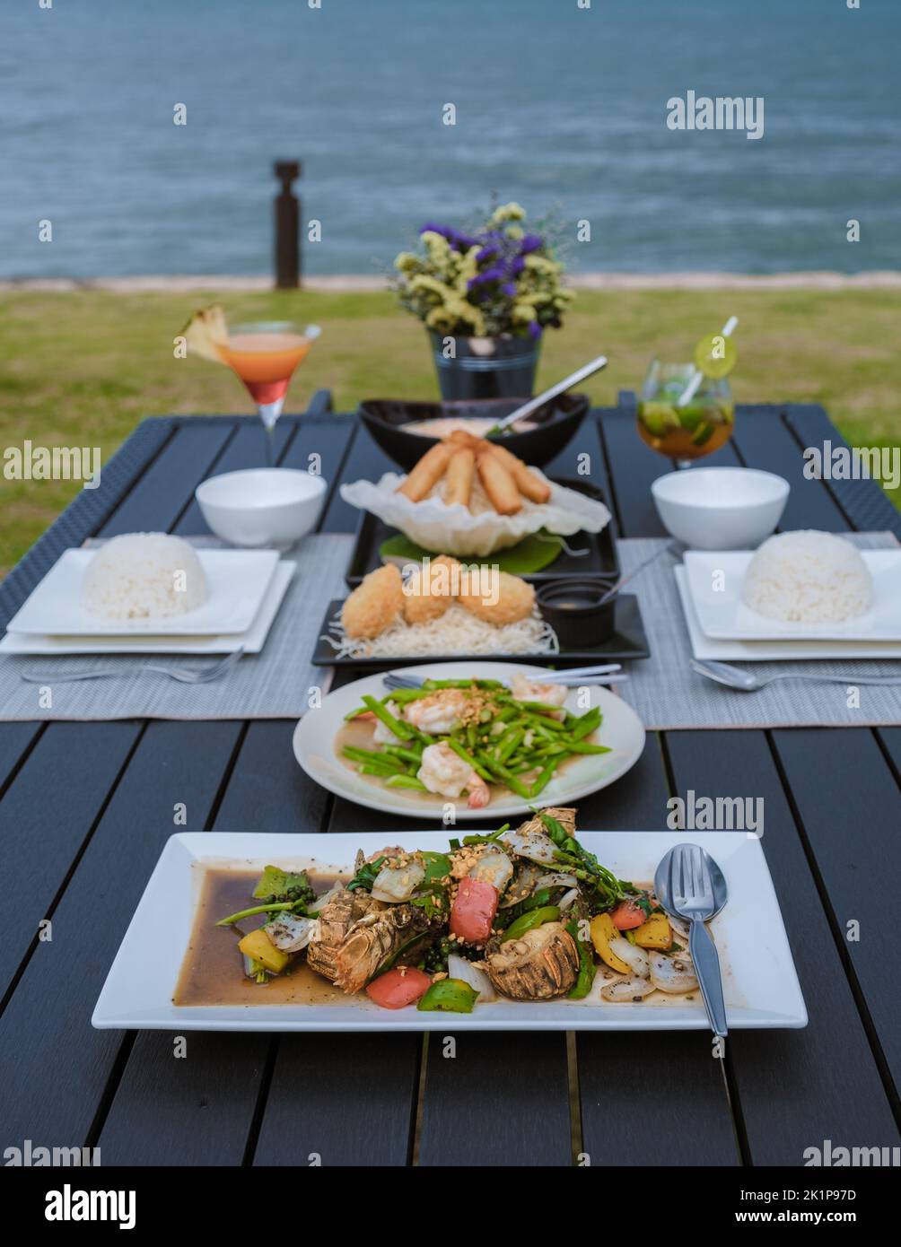 Luxury dinner table by the ocean with lobster, fish, and Thai food ...